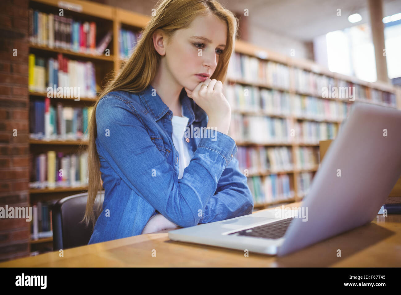 Focused student using laptop in library Stock Photo - Alamy