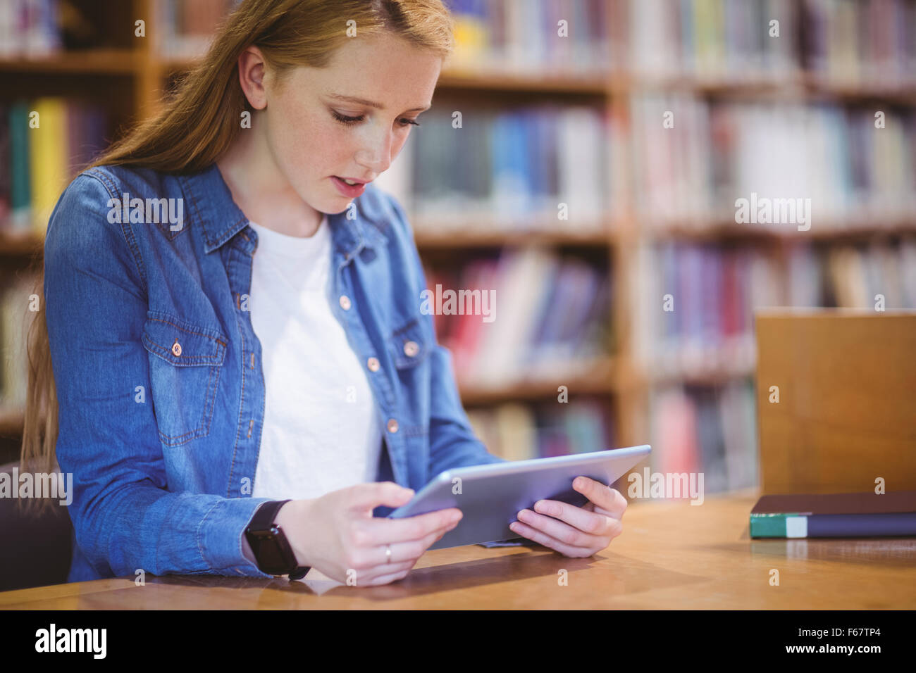 Student with smartwatch using tablet in library Stock Photo - Alamy