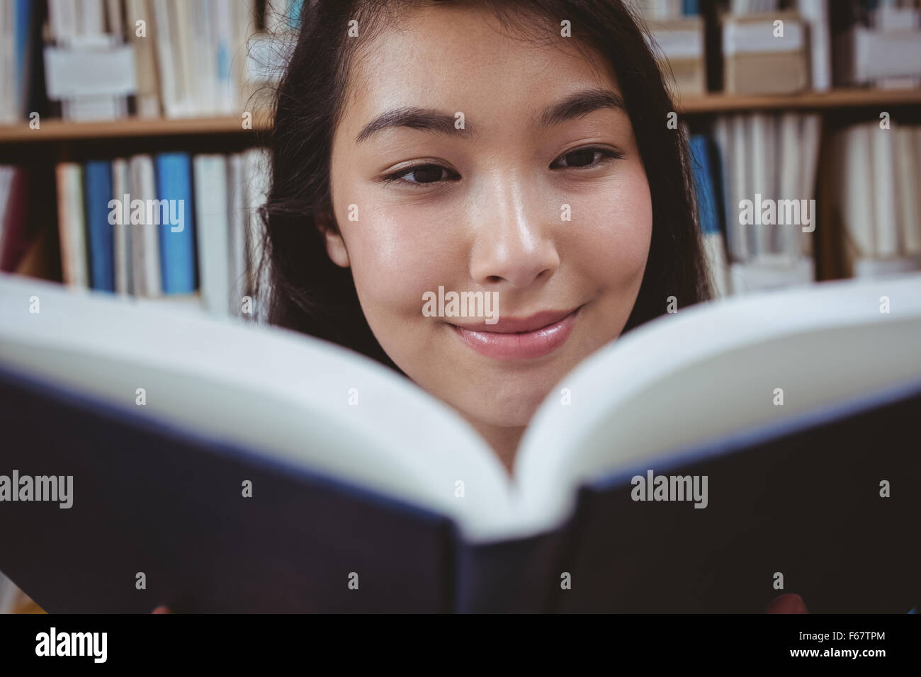 Smiling student reading a book Stock Photo - Alamy