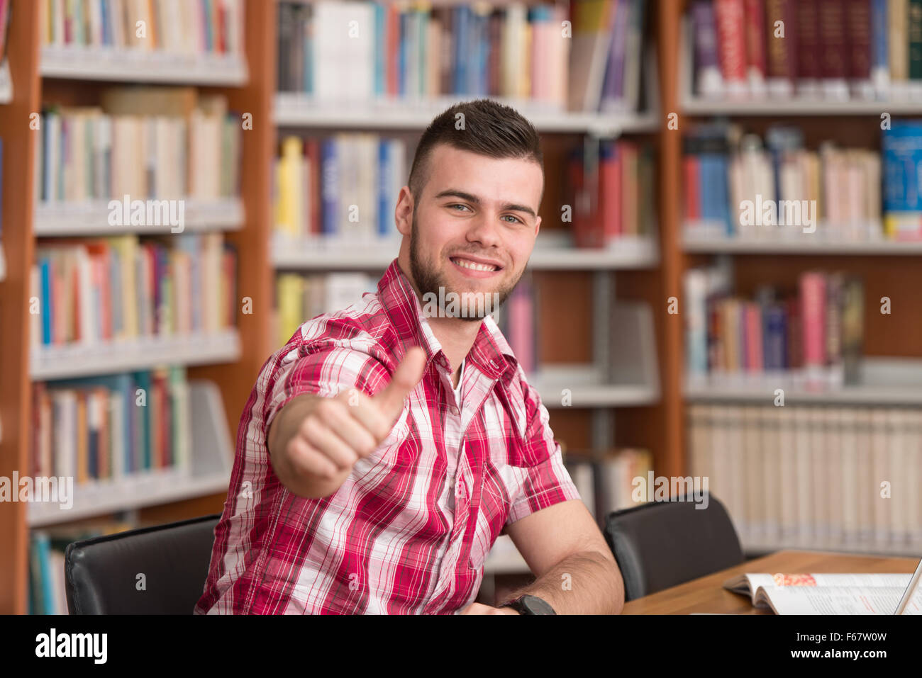 Portrait Of A Young Clever Student Showing Thumbs Up In College Library ...