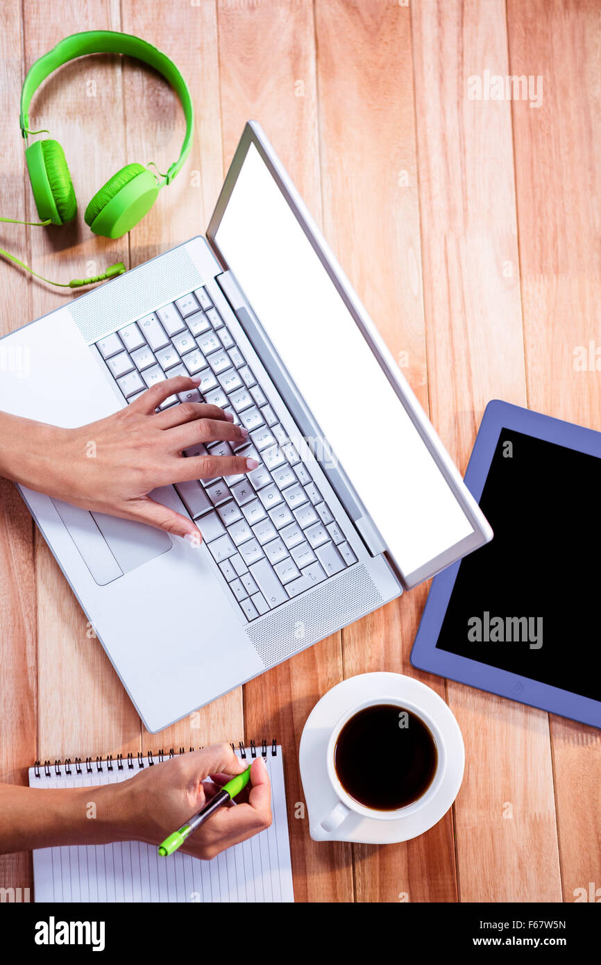 Overhead of feminine hand typing on laptop and taking notes Stock Photo ...