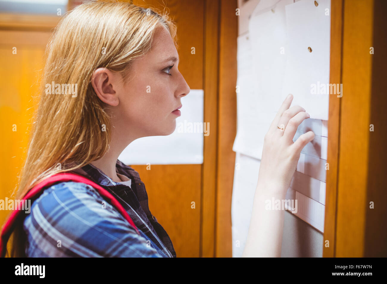 Pretty student looking at notice-board Stock Photo - Alamy
