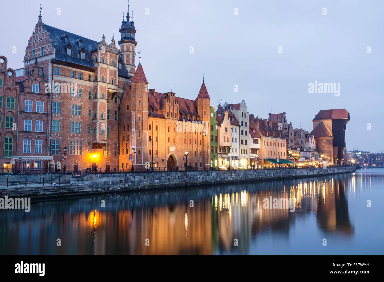 Waterfront tenements and crane reflected on Motlawa river at dusk ...