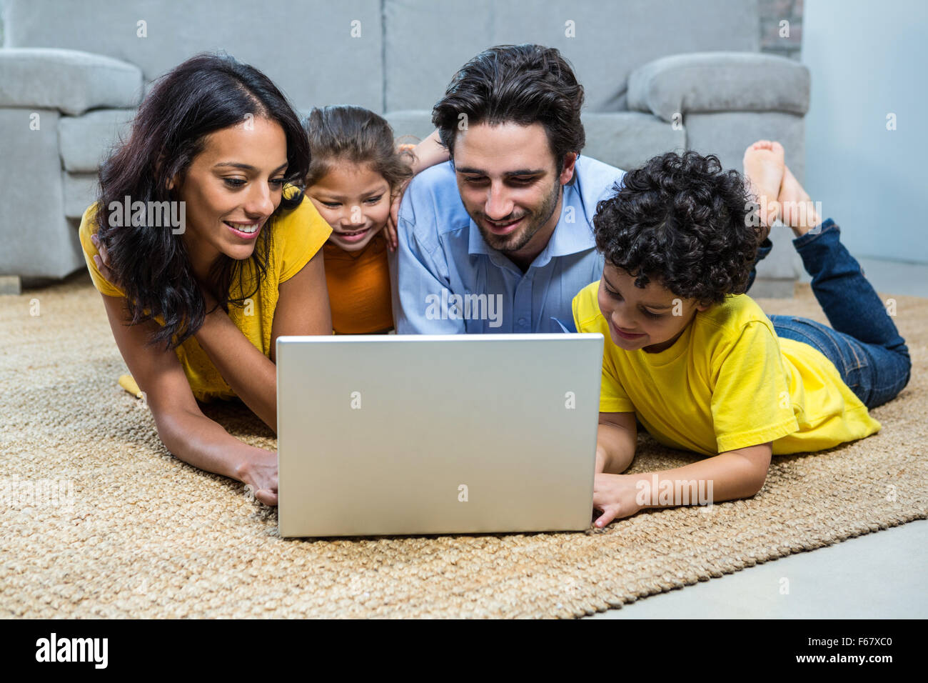 Smiling family using laptop in living room Stock Photo - Alamy