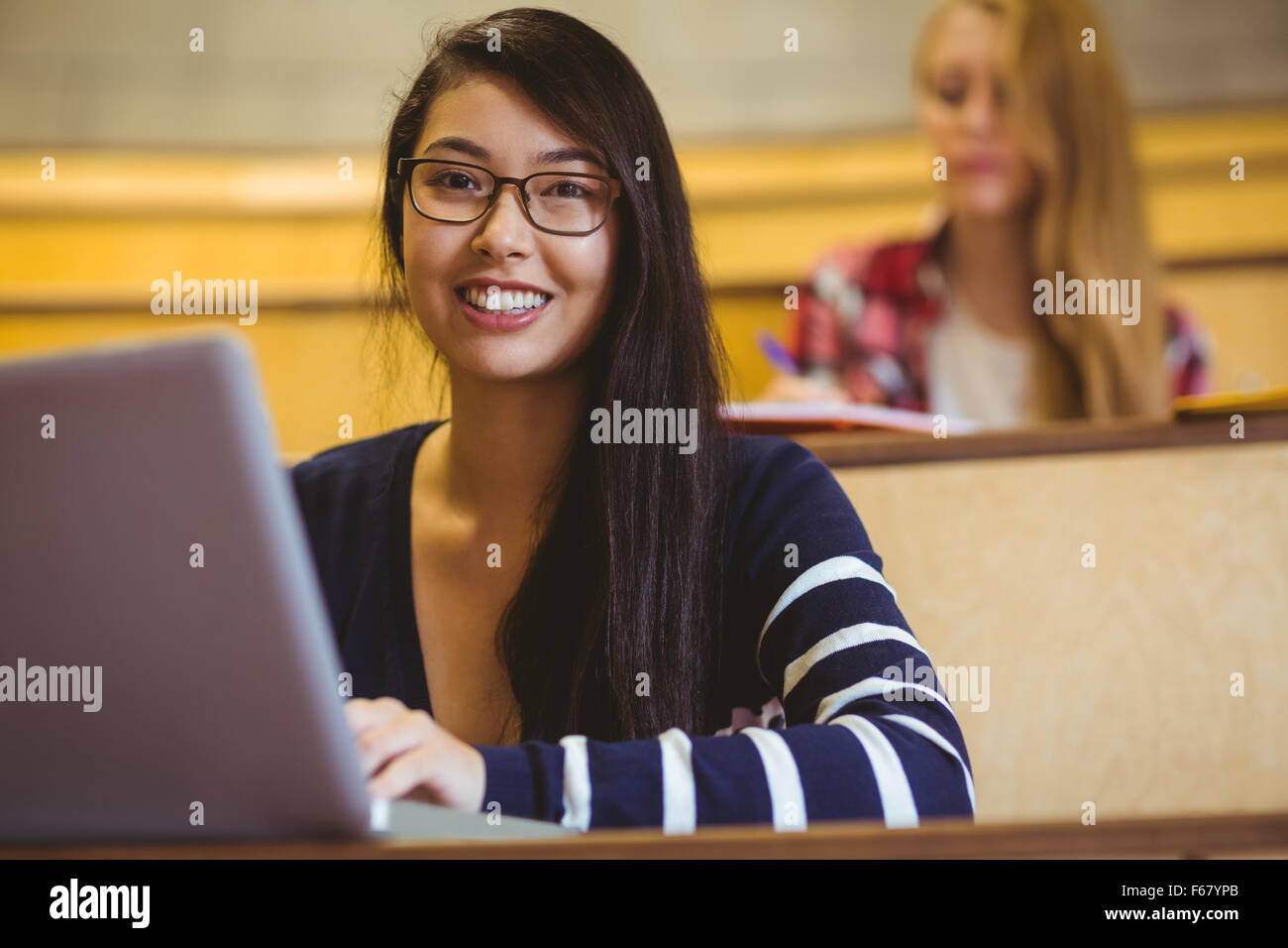 Smiling student using laptop during class Stock Photo - Alamy
