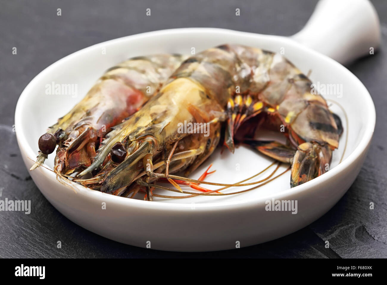 Raw unpeeled Giant Prawns in white china on a black slate background Stock Photo - Alamy