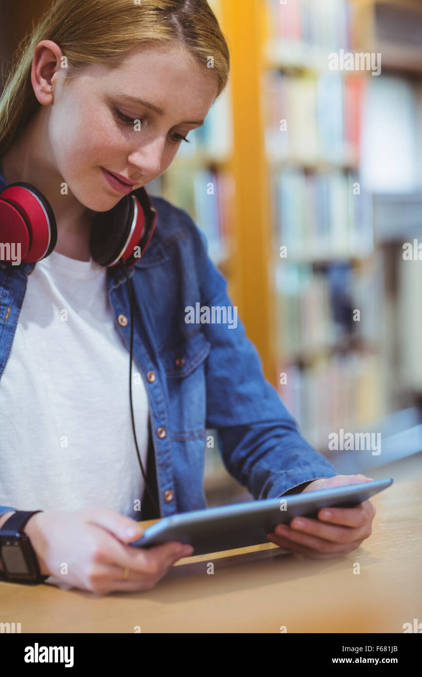 Pretty student with headphones using tablet in library Stock Photo - Alamy
