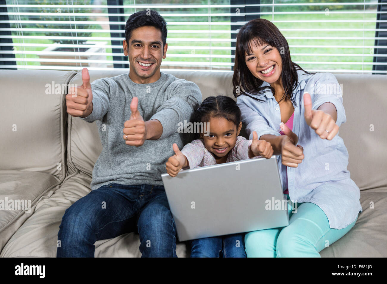 Happy young family using laptop with thumbs up Stock Photo - Alamy