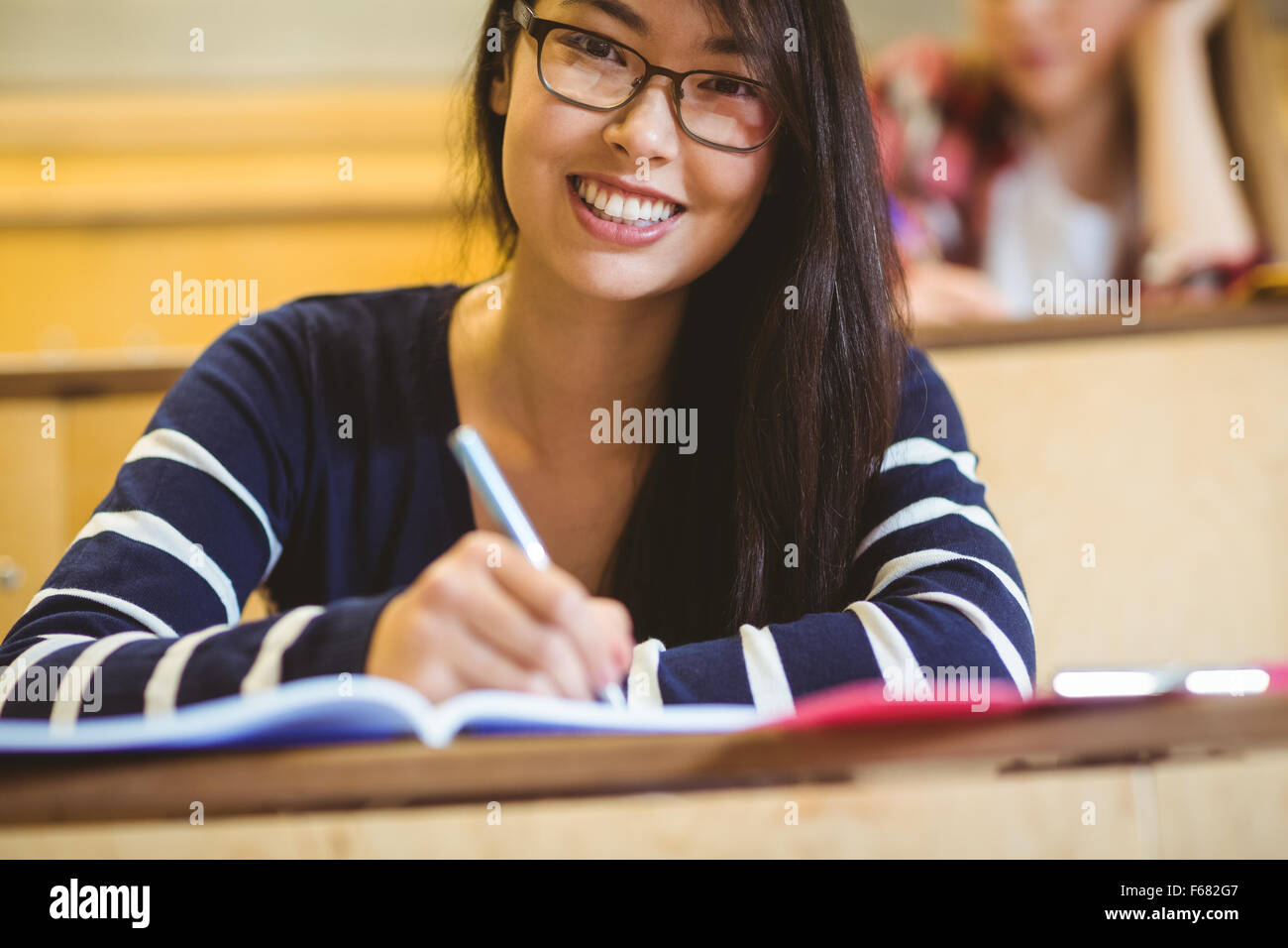 Smiling student writing on notebook Stock Photo - Alamy