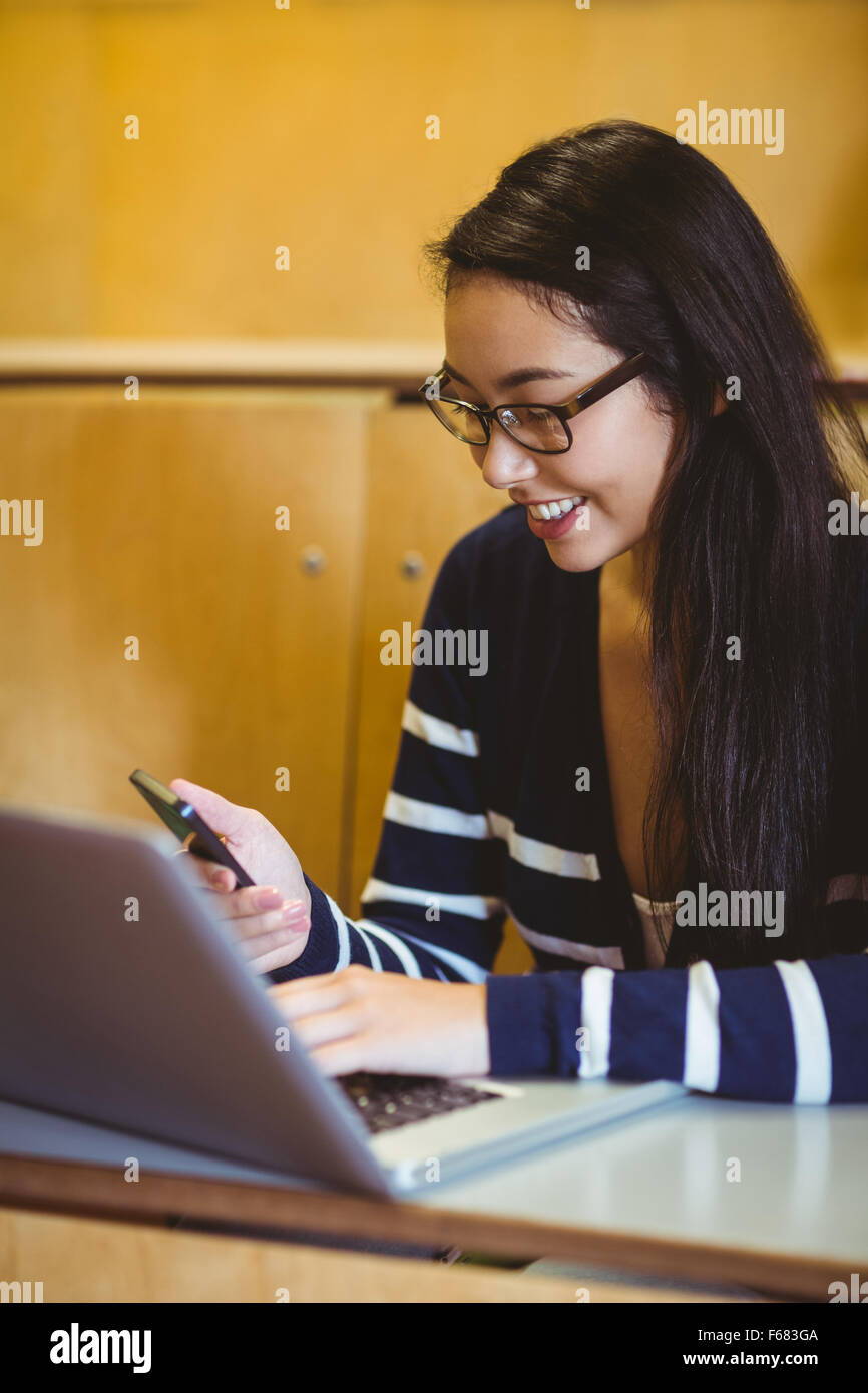 Smiling student using laptop and smartphone during class Stock Photo ...