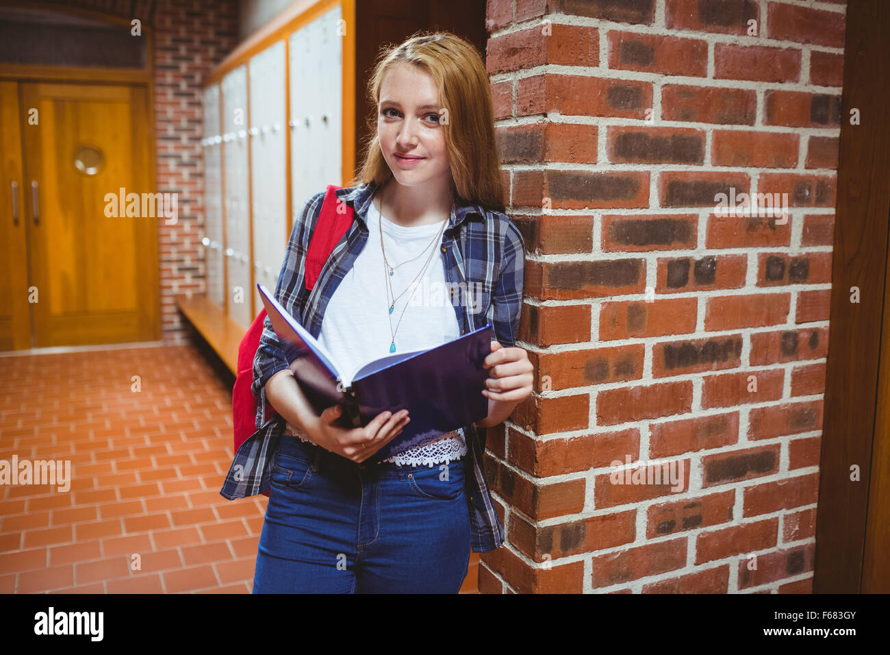 Smiling student studying leaning against the wall Stock Photo - Alamy
