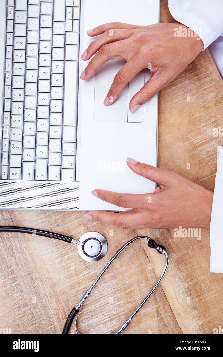 Doctor using laptop on wood desk Stock Photo - Alamy