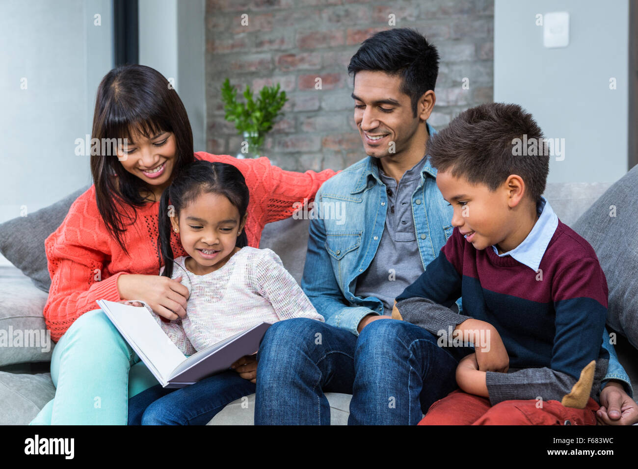 Happy young family reading a book together Stock Photo - Alamy