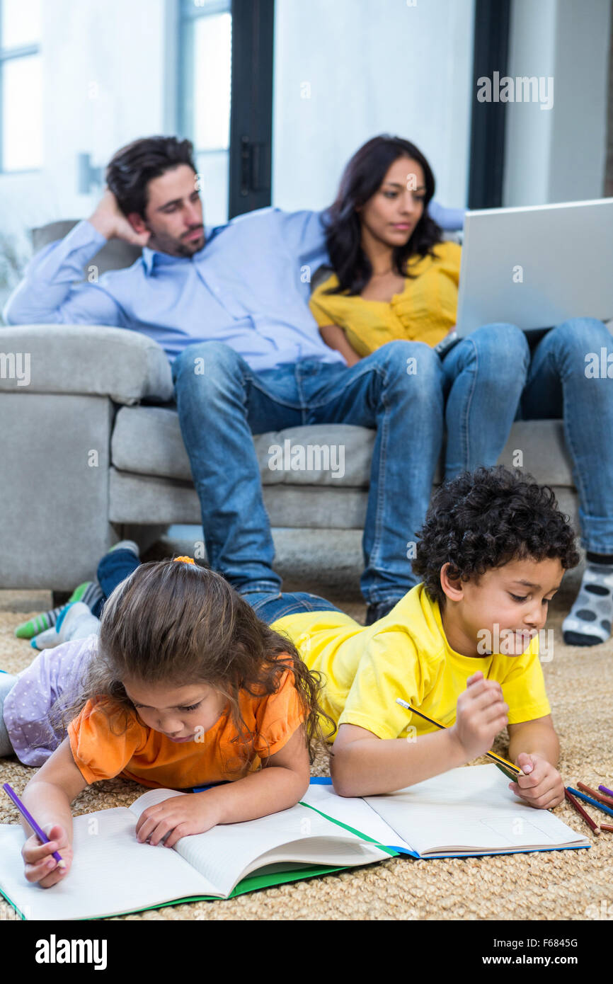 Children laying on the carpet drawing in living room Stock Photo - Alamy