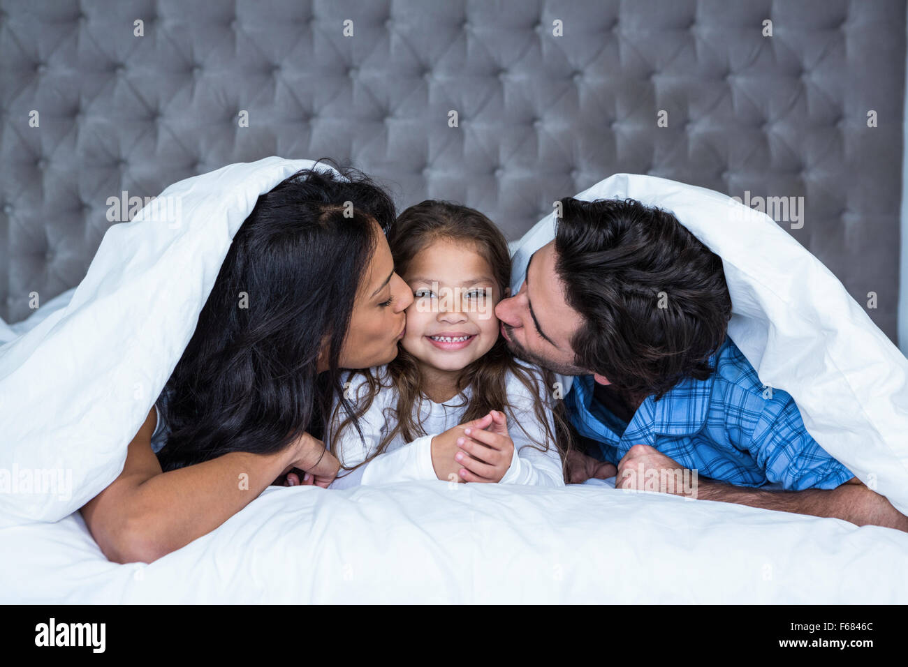 Happy parents kissing daughter Stock Photo - Alamy
