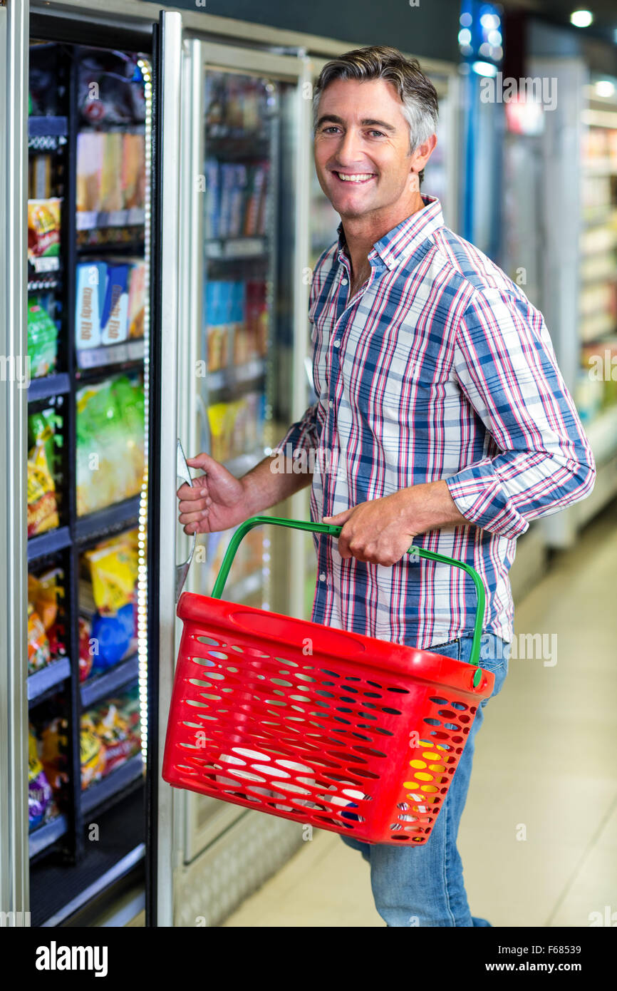 Smiling man opening supermarket fridge Stock Photo - Alamy