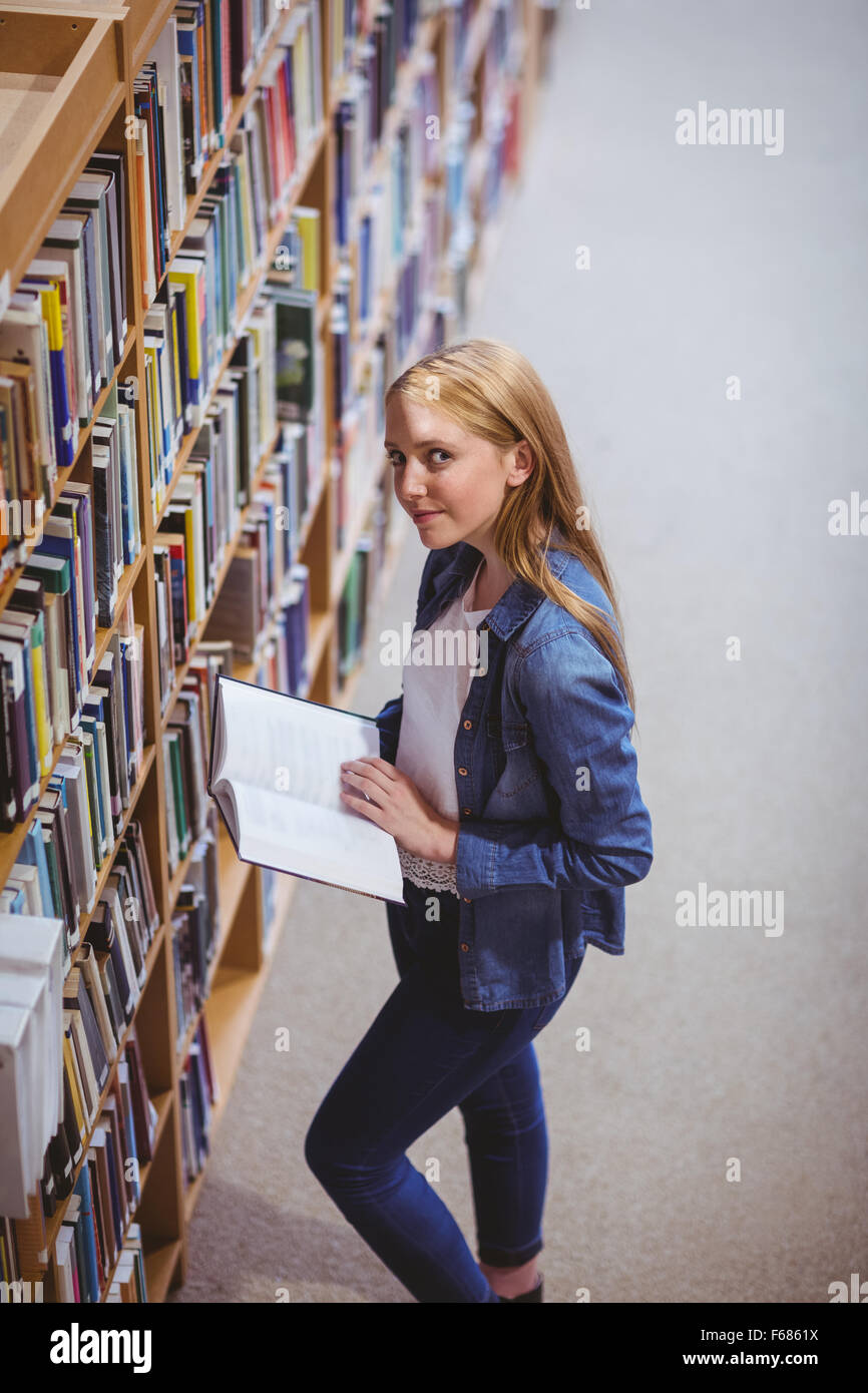 Standing student reading book in library Stock Photo - Alamy