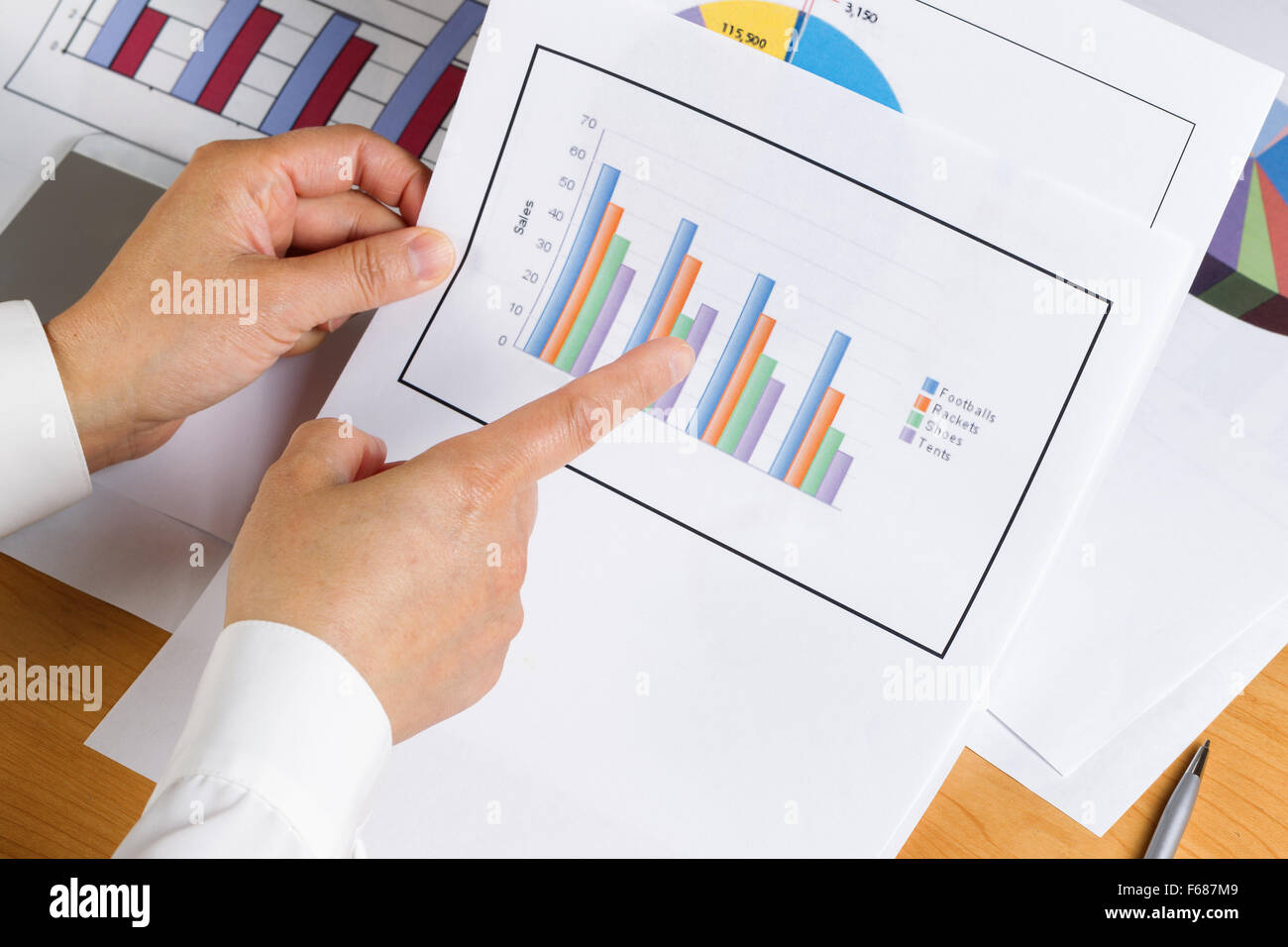 Woman hand pointing index finger at bar chart with printed graphs in ...
