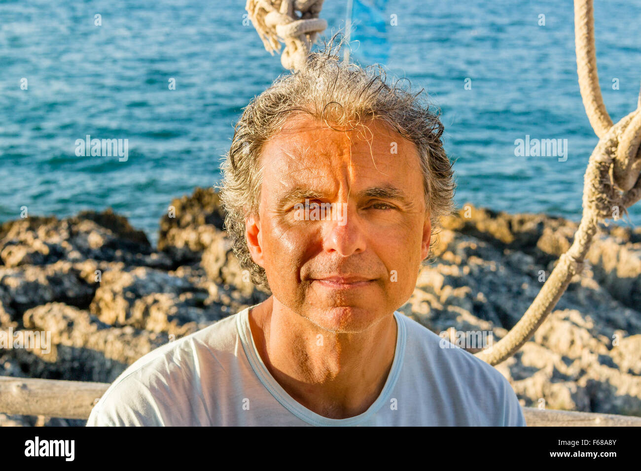 middle-aged adult with a three-day beard and t-shirt on the sea shore ...