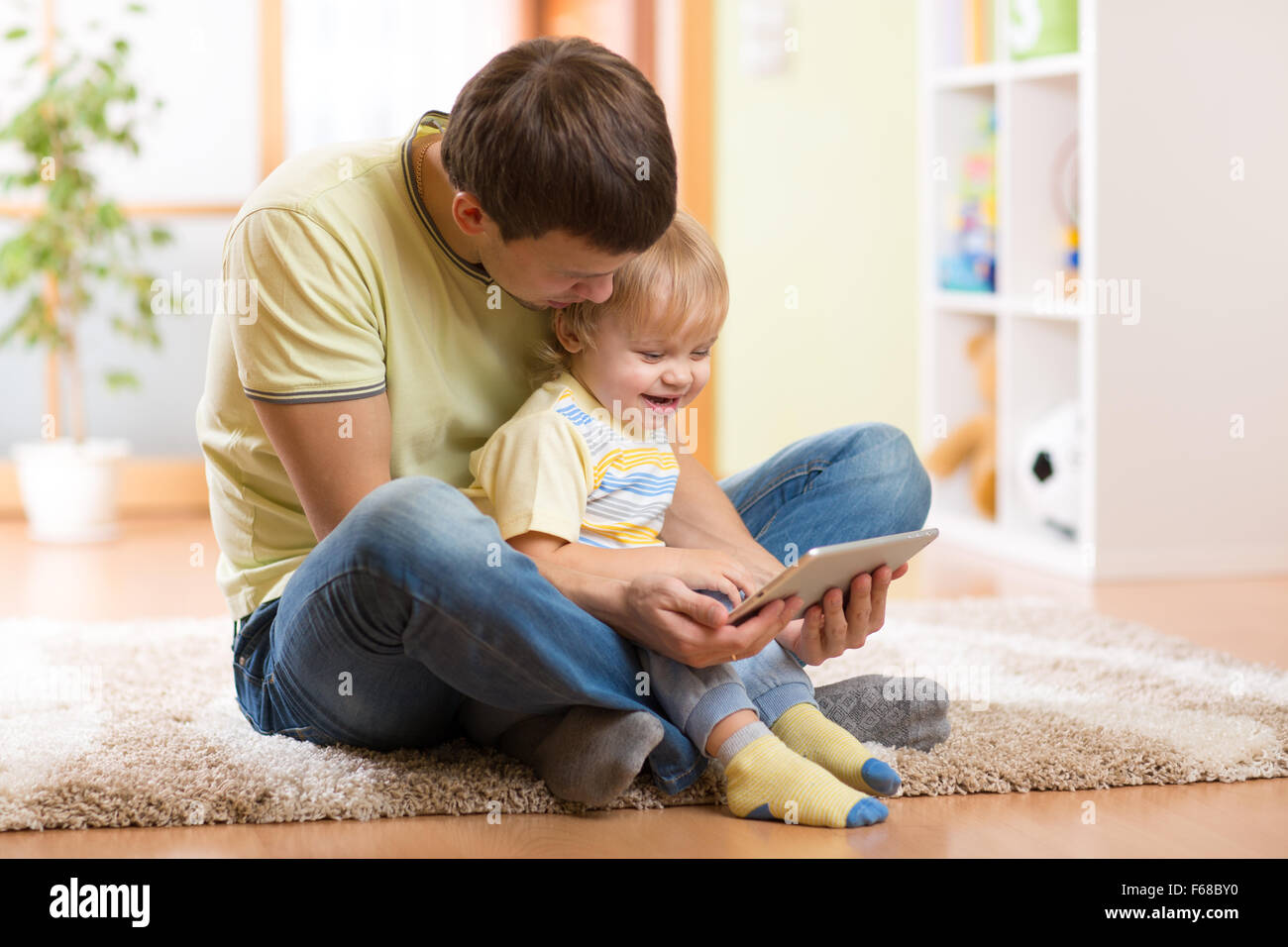 Daddy and son kid playing with tablet computer indoors Stock Photo - Alamy