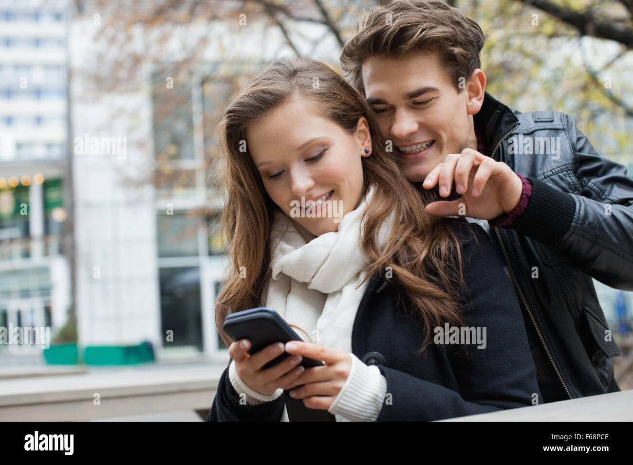 Couple In Winter Jackets Using Mobile Phone Stock Photo - Alamy