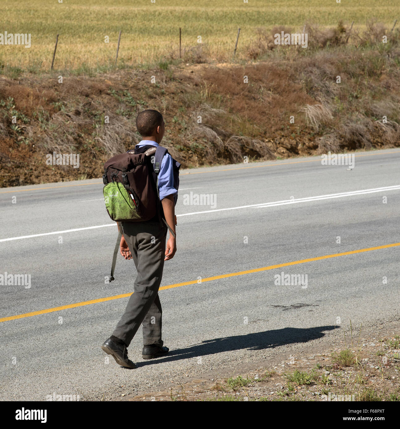 Schoolboy carrying a rucksack walking to school along an African ...