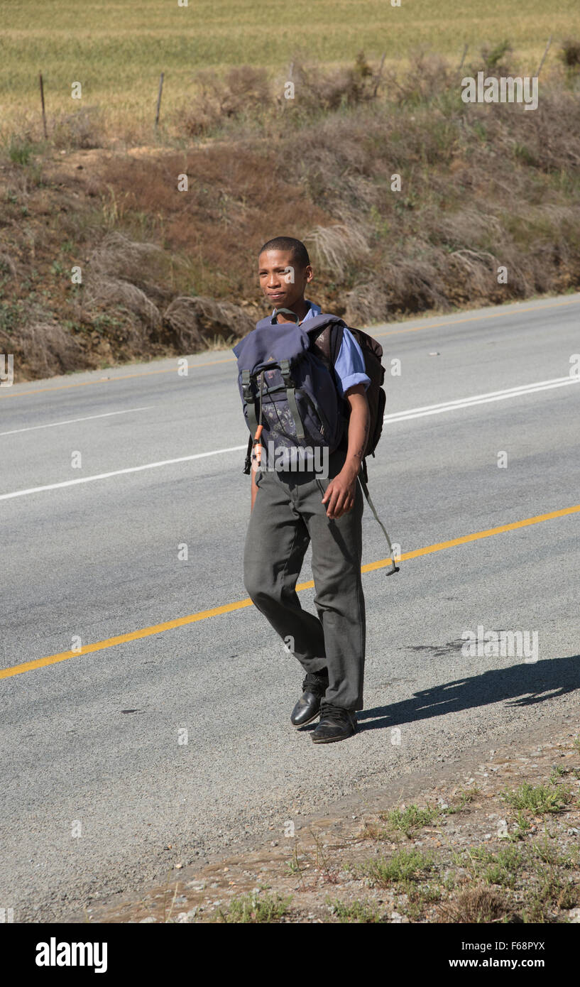 Schoolboy carrying a rucksack walking to school along an African ...