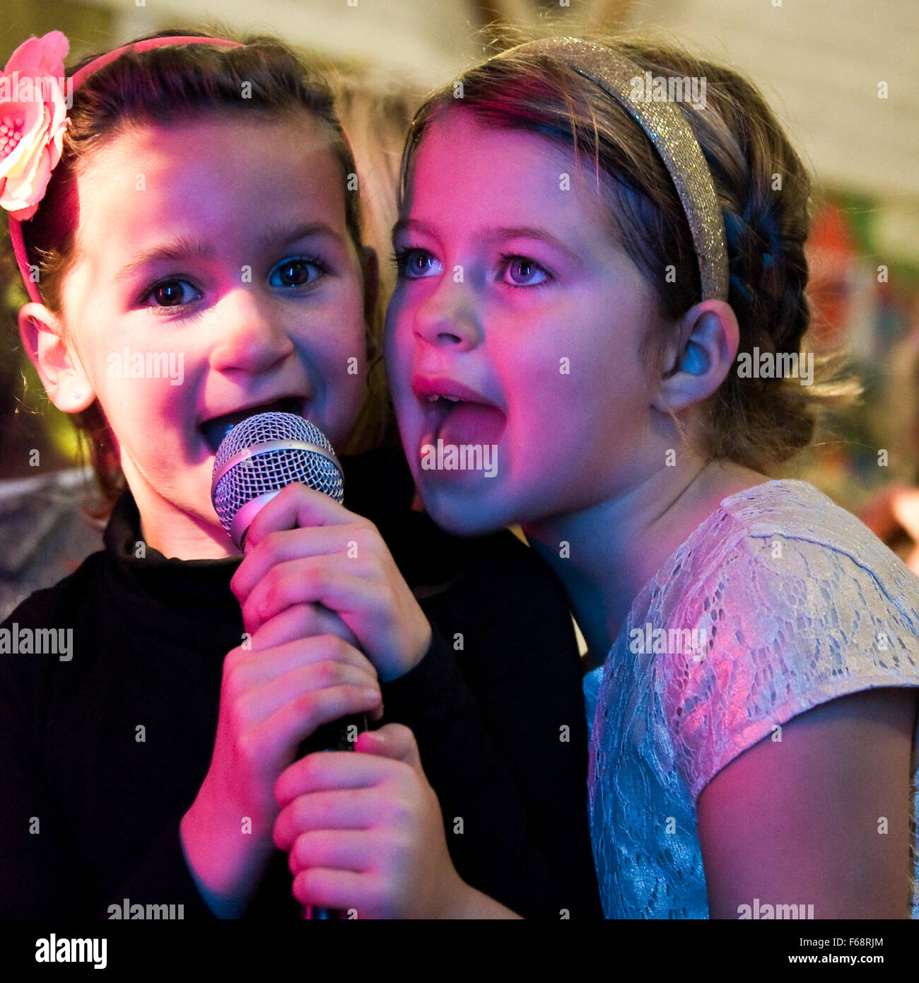 Square portrait of young girls singing karaoke at a birthday party ...
