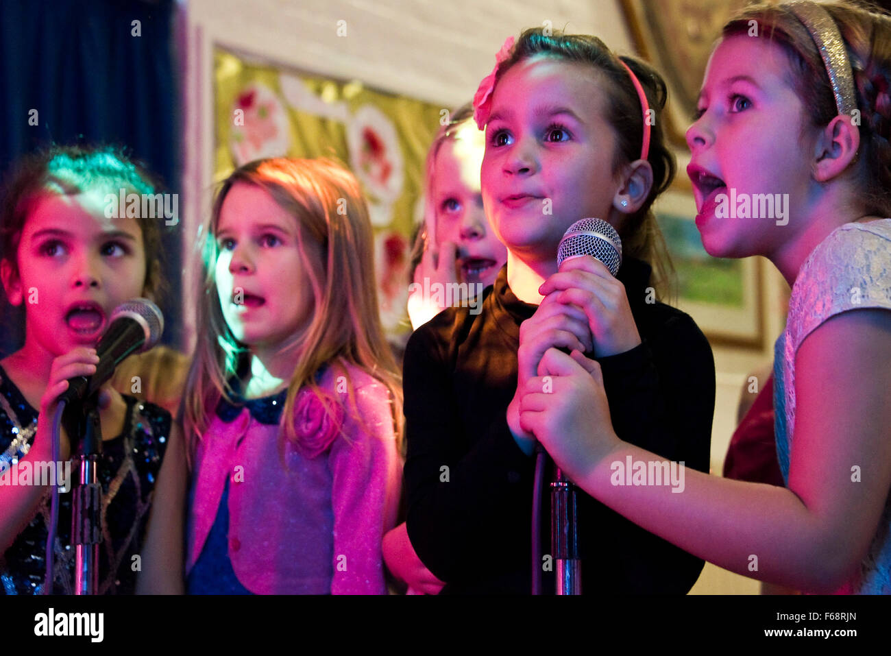 Horizontal portrait of young girls singing karaoke at a birthday party ...