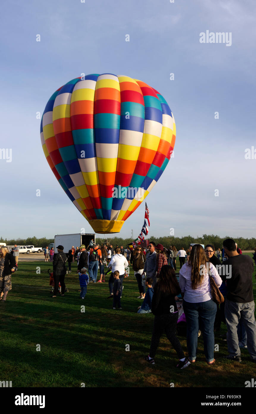 One floating balloon still tethered to the ground as crowd wanders ...
