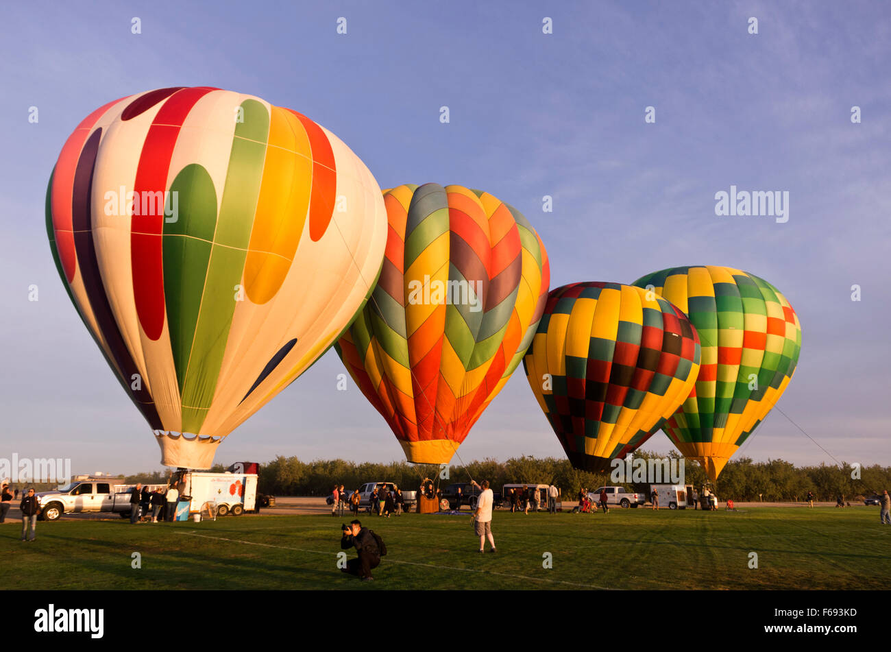 4 tethered balloons getting ready to ascend, crowd below on field Stock ...
