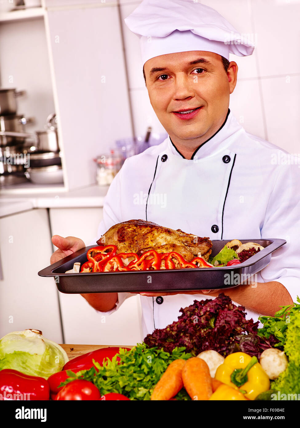 Man in chef hat cooking chicken Stock Photo - Alamy