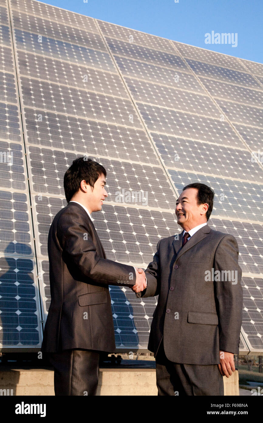 Shaking hands in front of solar panels Stock Photo - Alamy