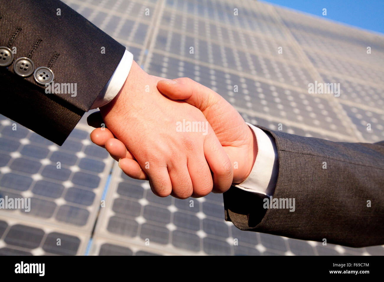 Shaking hands in front of solar panels Stock Photo - Alamy