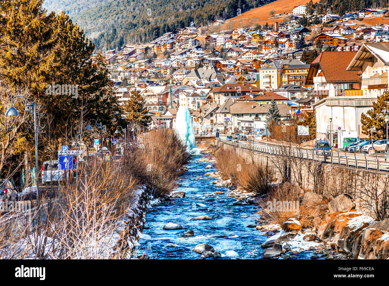 River passing through snowy alpine village in Italy illuminated by sun ...