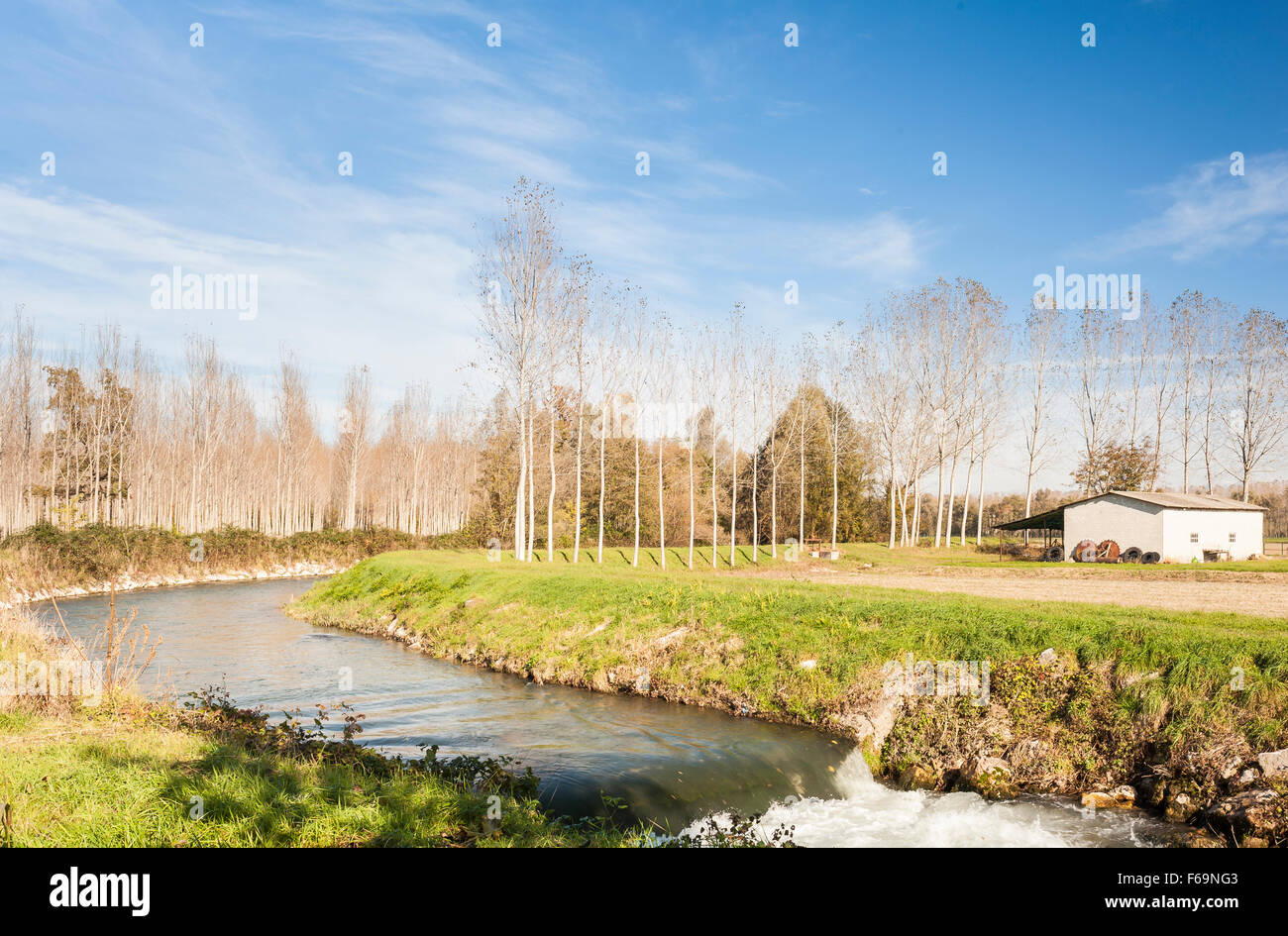 Agricultural landscape with a river, waterfall, poplars and an old tool ...