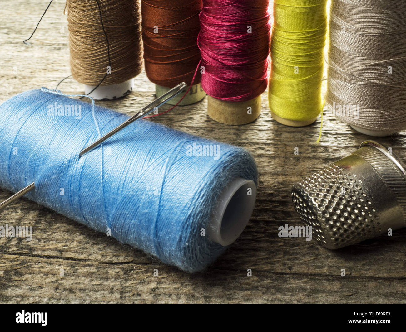Nov. 15, 2015 - Threads, sewing needle and thimble on old weathering ...