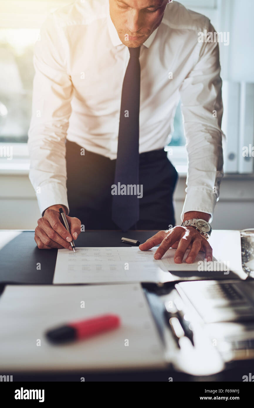 Business man closing a deal signing documents at desk in office wearing ...