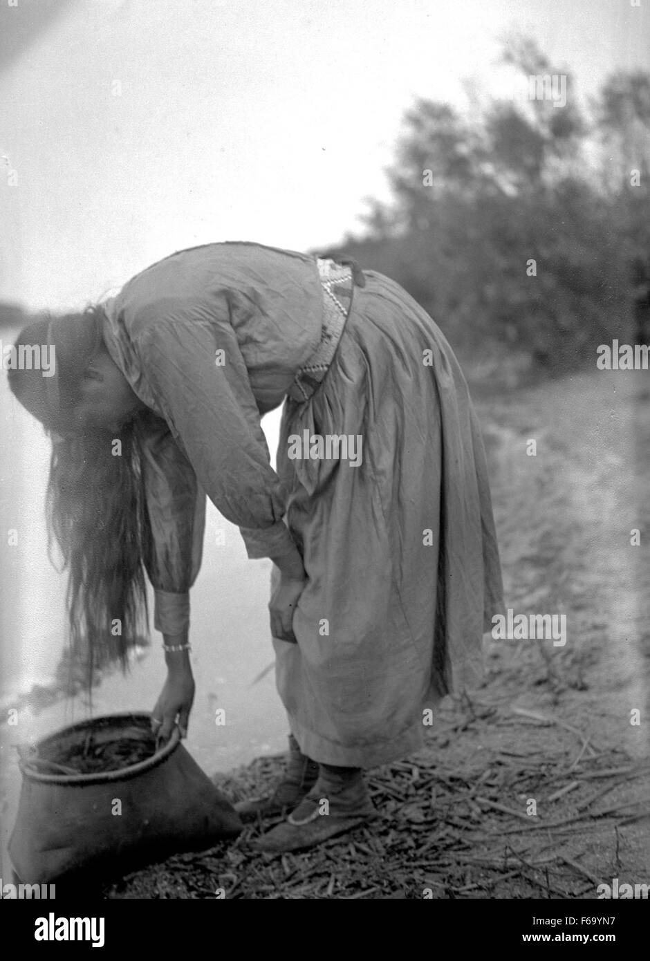 A young Cree woman is shown holding a traditional birch bark container ...