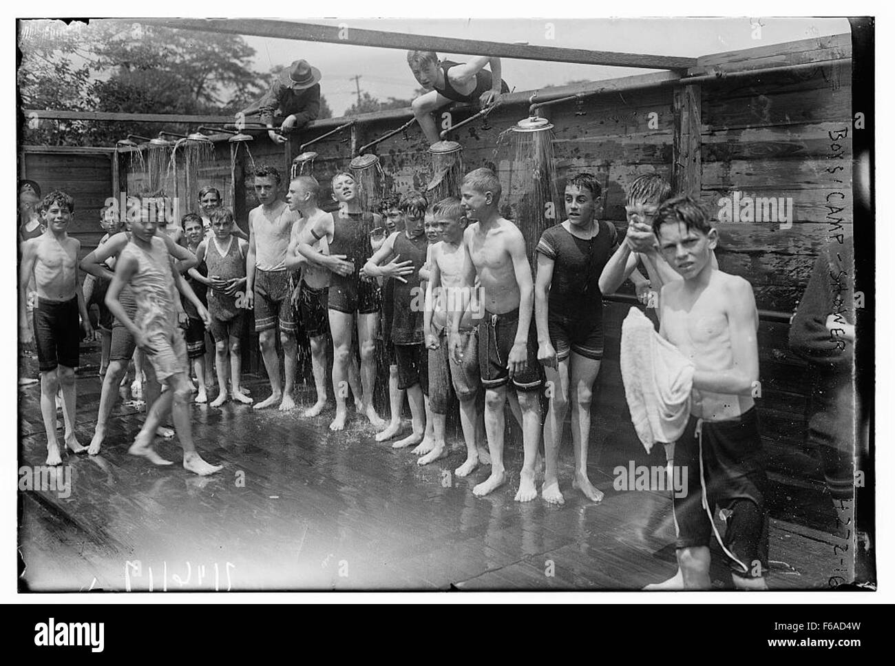 At a boy's camp, children are seen using outdoor showers. This captures ...