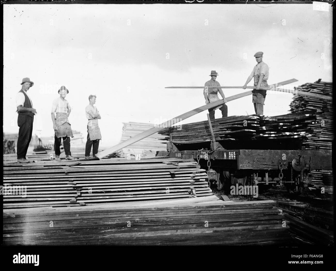 Workers are seen loading timber onto a railway bogie in a sawmill yard ...