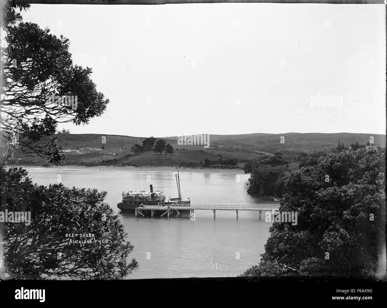 This photograph captures a ferry steamer docked at Waiake Beach in ...