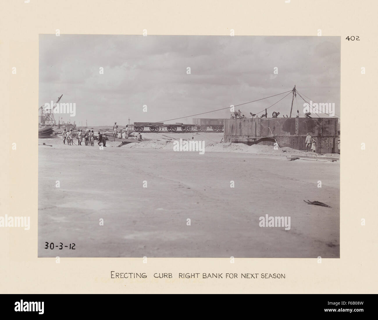 A photograph showing workers constructing a curb on the right bank of a ...