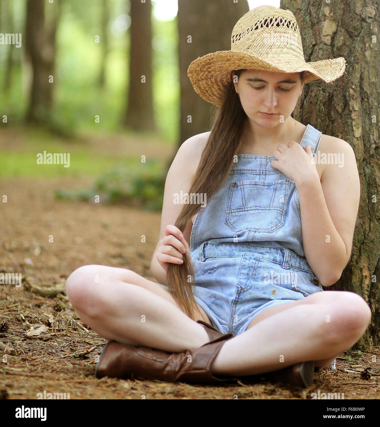 Country backwoods girl in old cut dungaree shorts in the woods, July ...