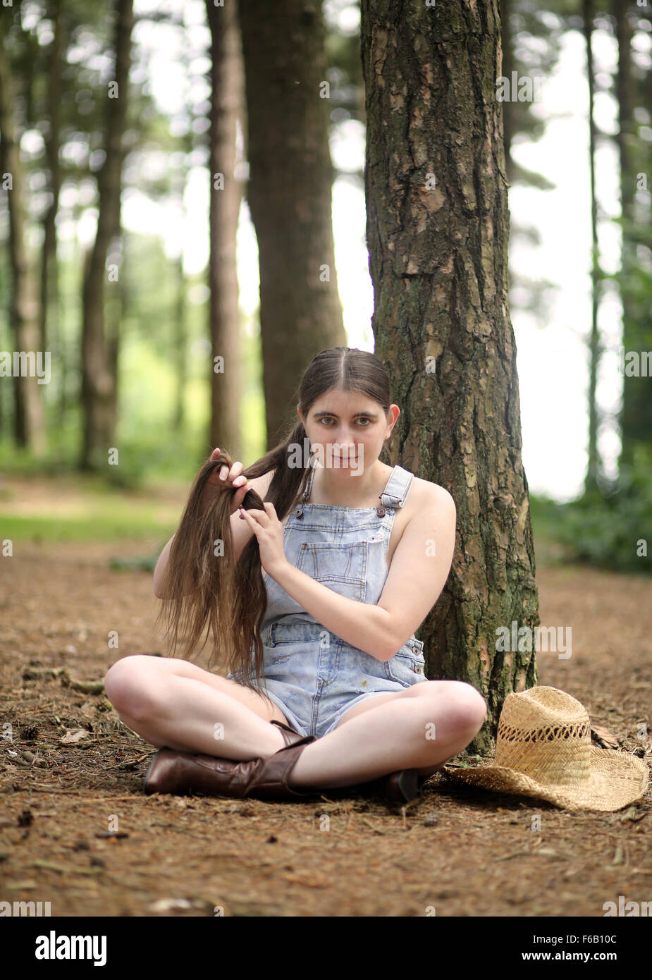 Country backwoods girl in old cut dungaree shorts in the woods, July ...
