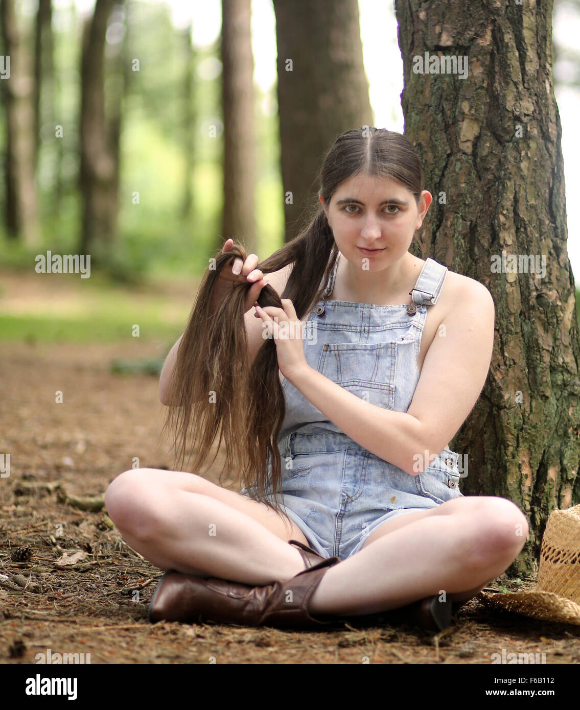Country backwoods girl in old cut dungaree shorts in the woods, July ...