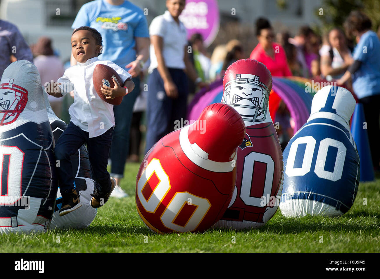 A young boy runs with a football through inflatable tackling dummies ...