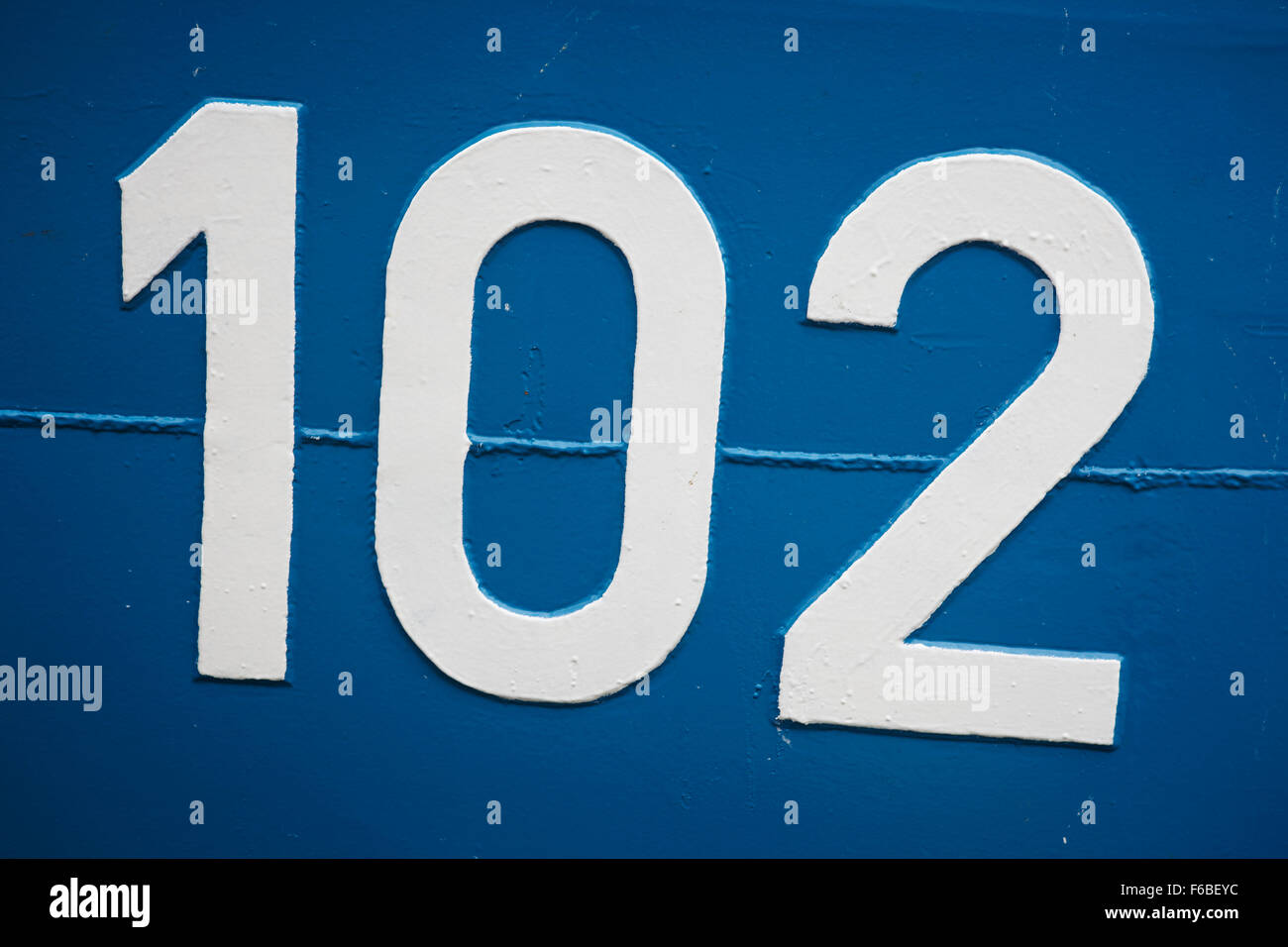 Number 102 painted on white against metallic blue surface Stock Photo ...