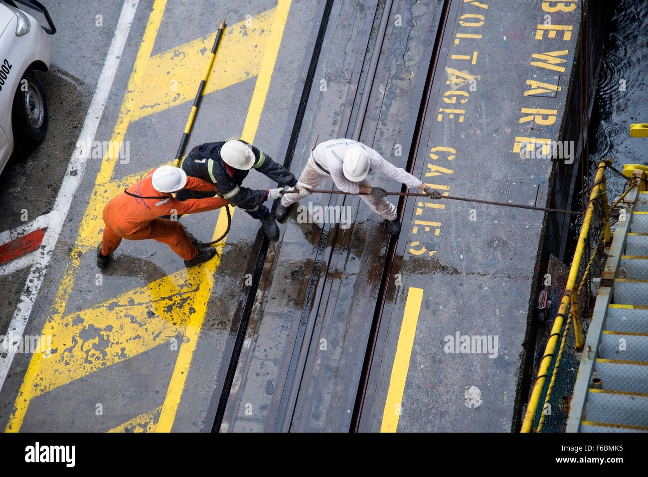 Workers pull hard on the rope to close the gap between Container ship ...