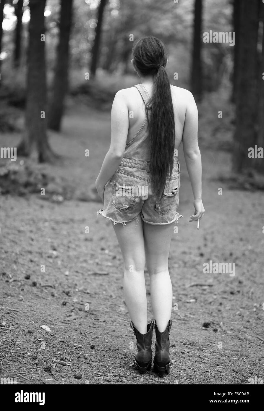 Country backwoods girl in old cut dungaree shorts in the woods, July ...